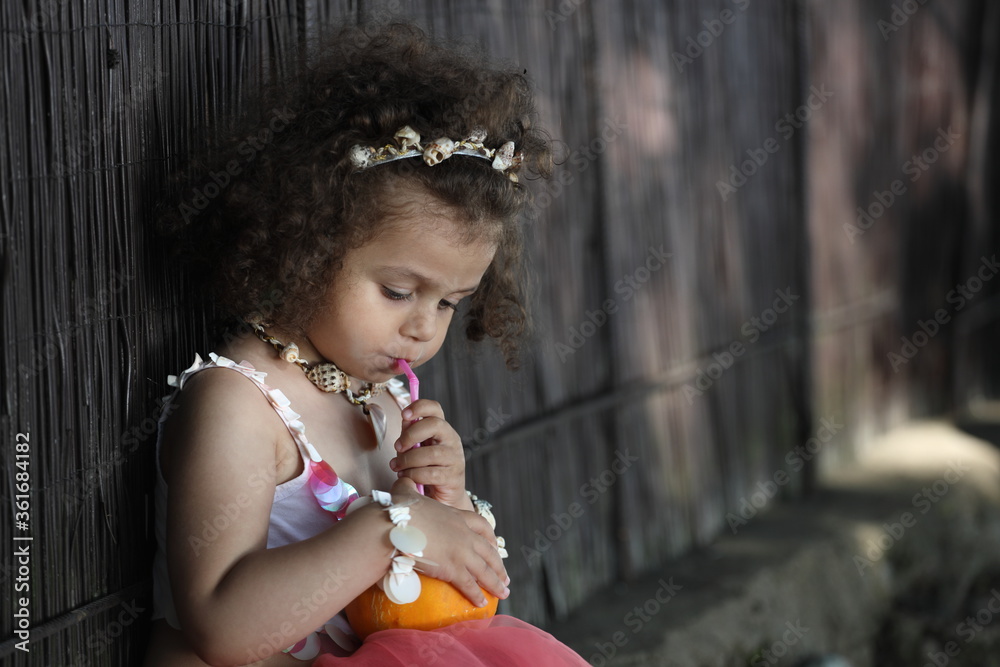 curly girl holding a melon with an inserted tube in her hands. Tropical ...
