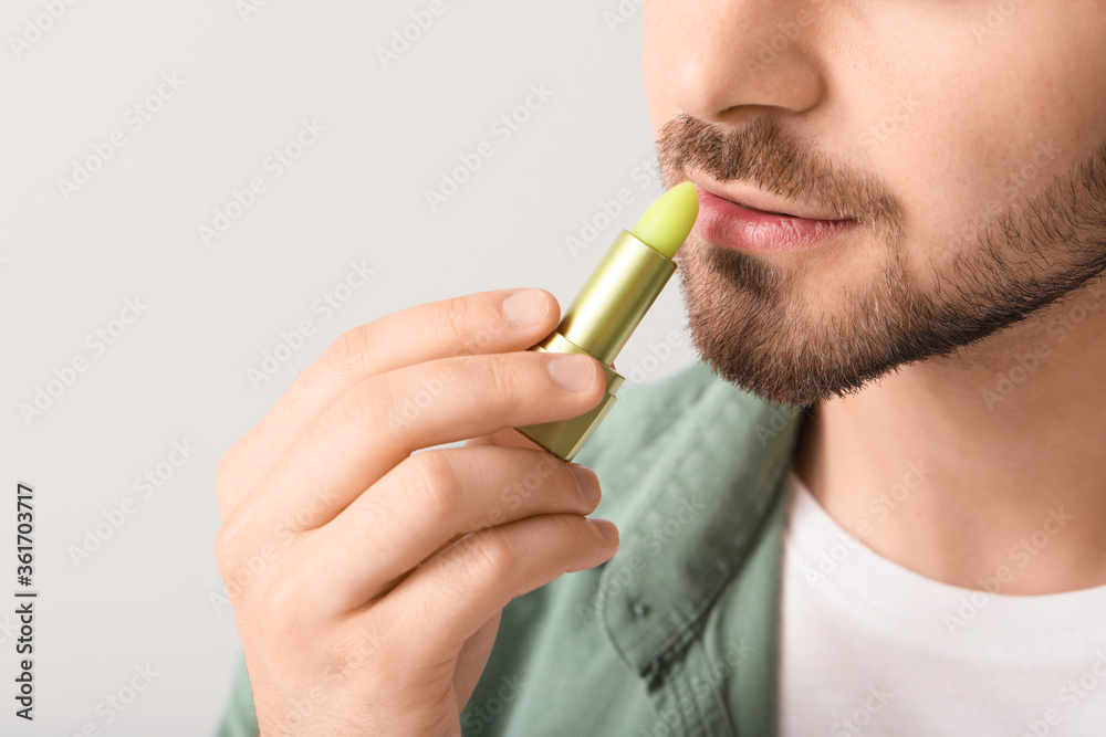 Handsome young man with lip balm on light background, closeup Stock ...