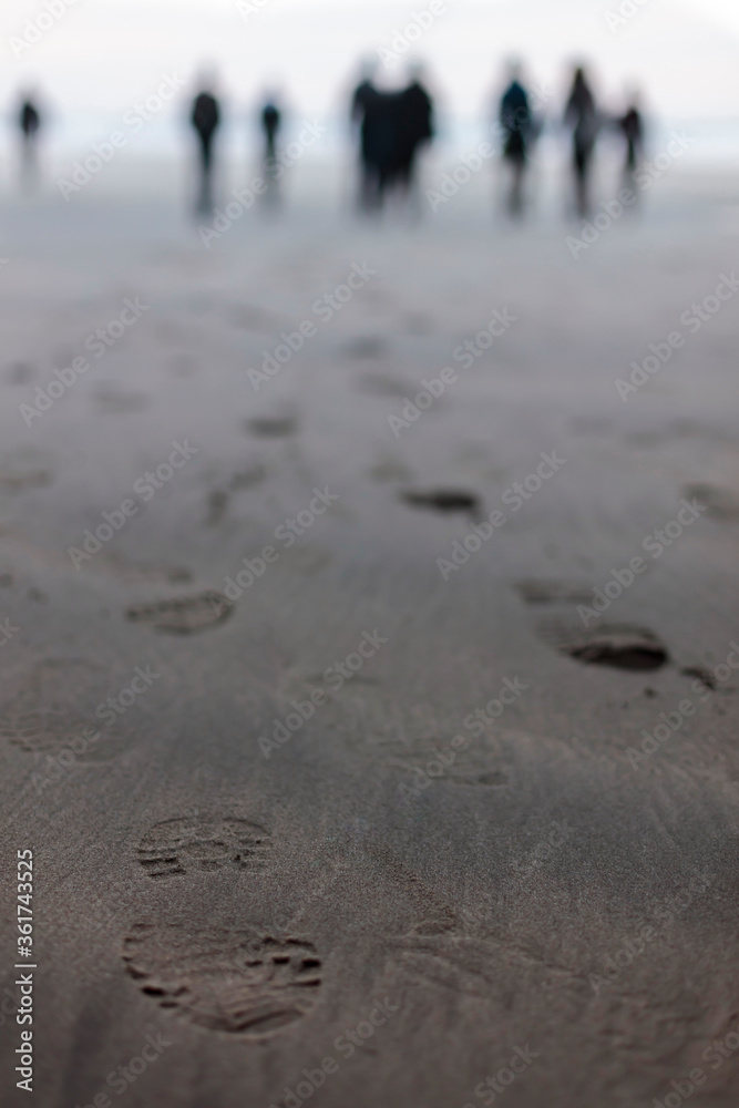 Shoe footprints on the beach sand left by a unknown group of people ...