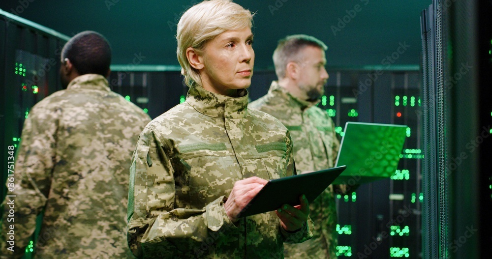 Caucasian military female officer in camouflage standing in server room ...