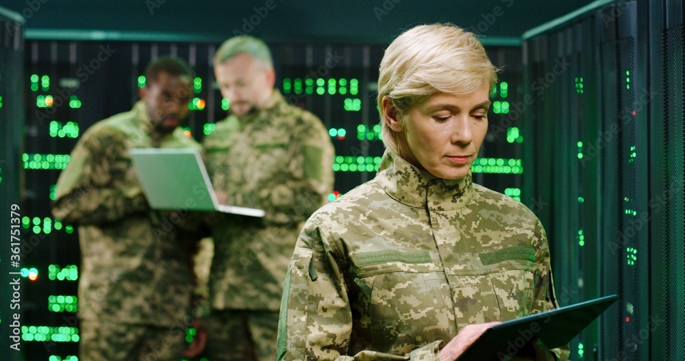 Caucasian military female officer in camouflage standing in server room ...
