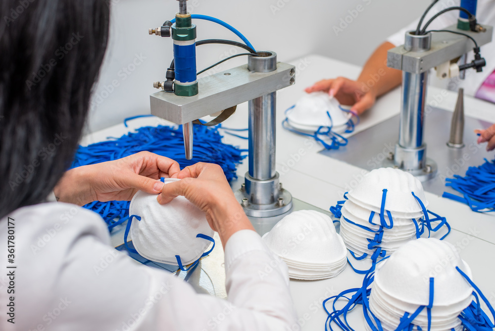 Women work at a machine for the manufacture of medical masks with ...