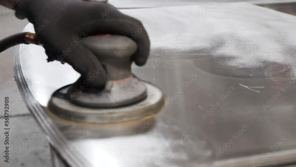 Hand using polishing tool to buff a metal sheet. Close up video of the ...