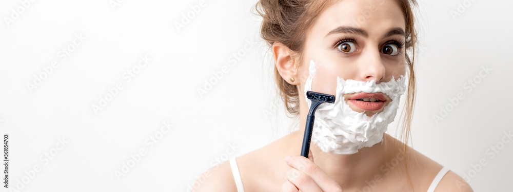 Beautiful young caucasian woman shaving her face by razor on white ...