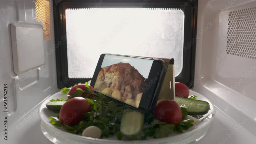 Plate with salad and cellphone with cooking food footage on screen in ...