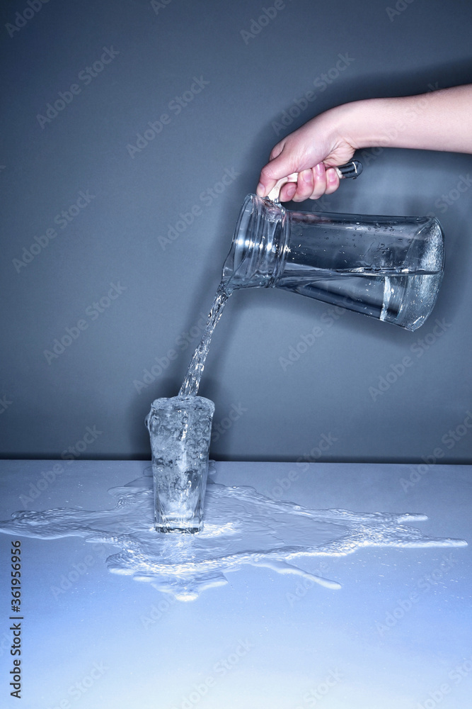 Human hand pouring water into an overflowing glass Stock Photo | Adobe ...