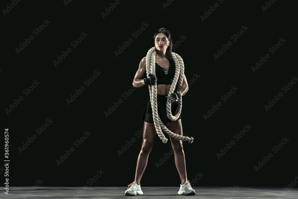 Beautiful young female athlete practicing on black studio background ...