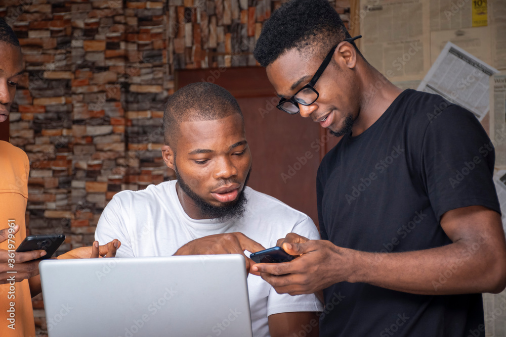 three african people, men, using mobile phones and laptop computer ...