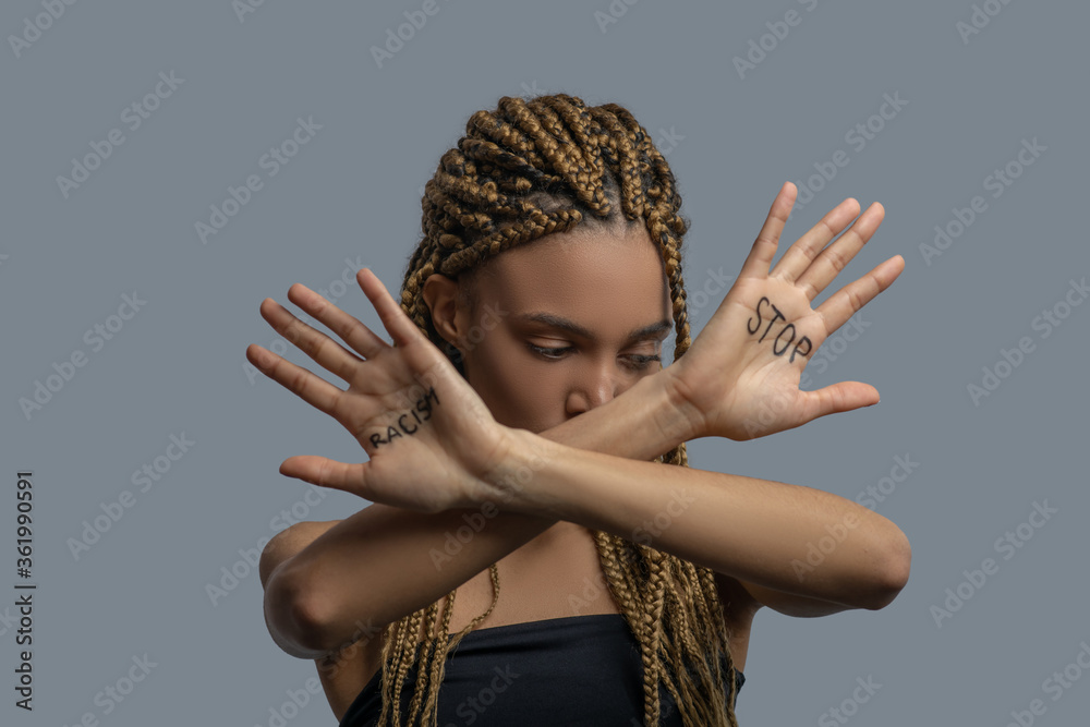 Young African American woman looking down, making cross with arms ...