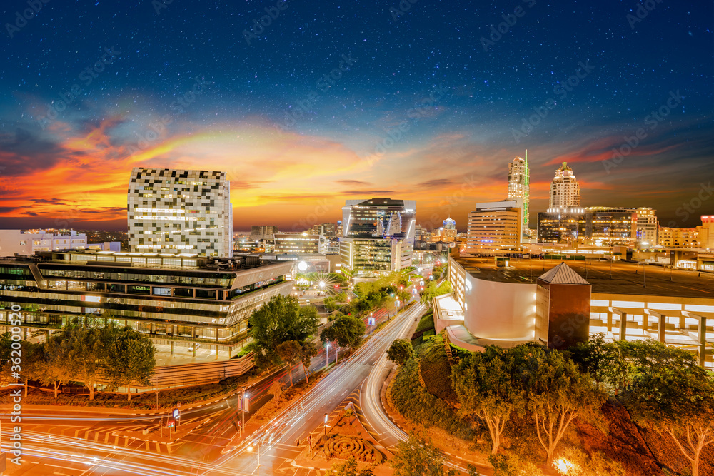 Sandton City lit up at night with colourful clouds and stars in the sky ...