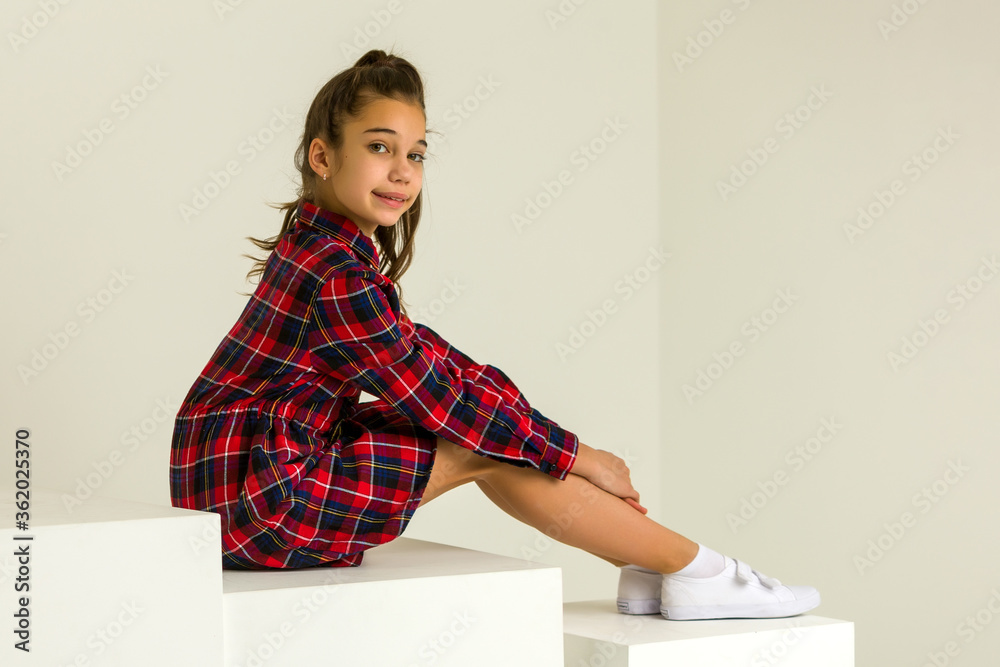 Cute little girl is sitting in the studio on the white stairs. style ...