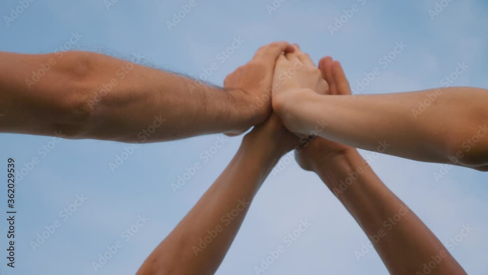 A group of successful people raise their hands up and hold hands ...