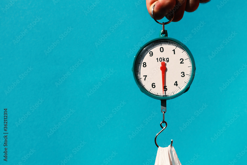 Round spring scales on a blue background show exactly five kilograms. A ...