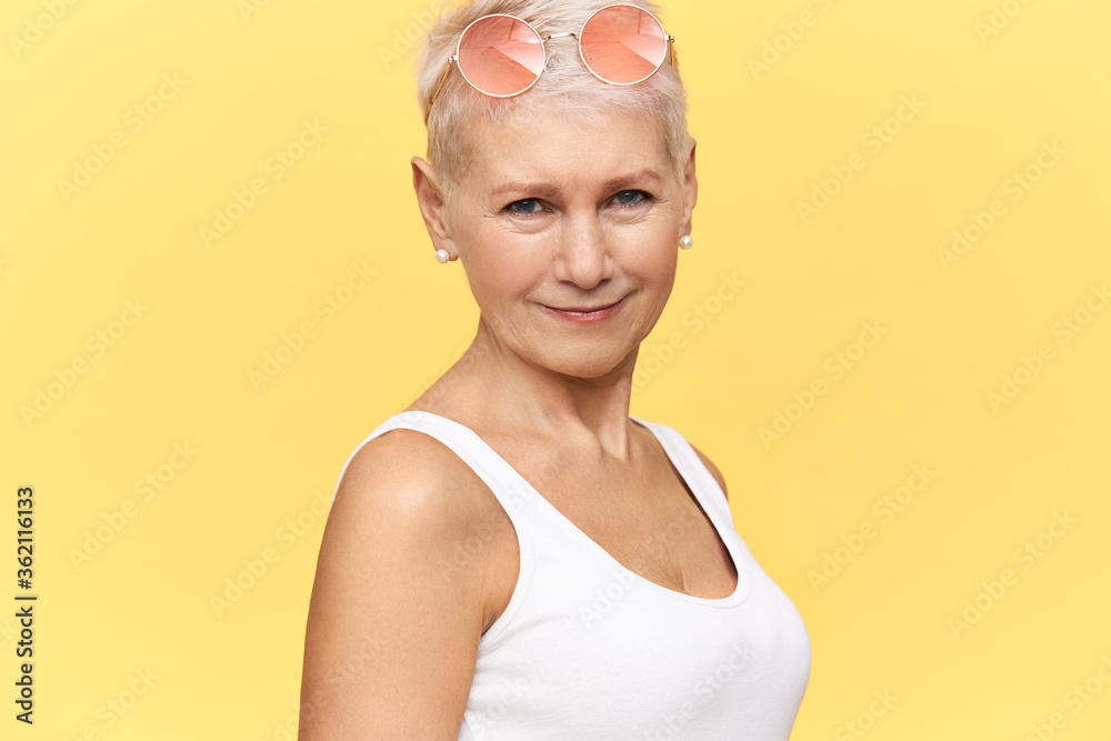 Attractive 50 year old European female posing against yellow background ...