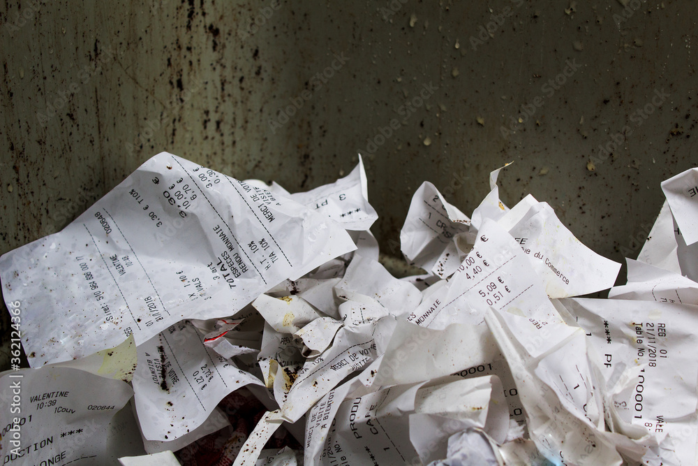 crumpled store receipts into street trash can under rain, consumerism ...