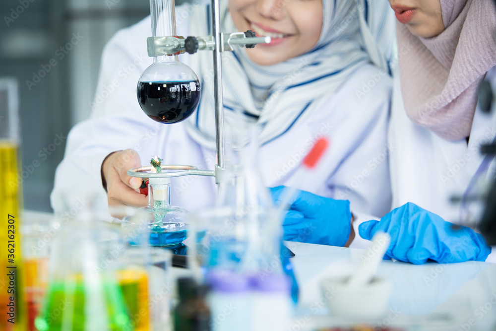 Muslim women scientists making an experiment in laboratory together ...