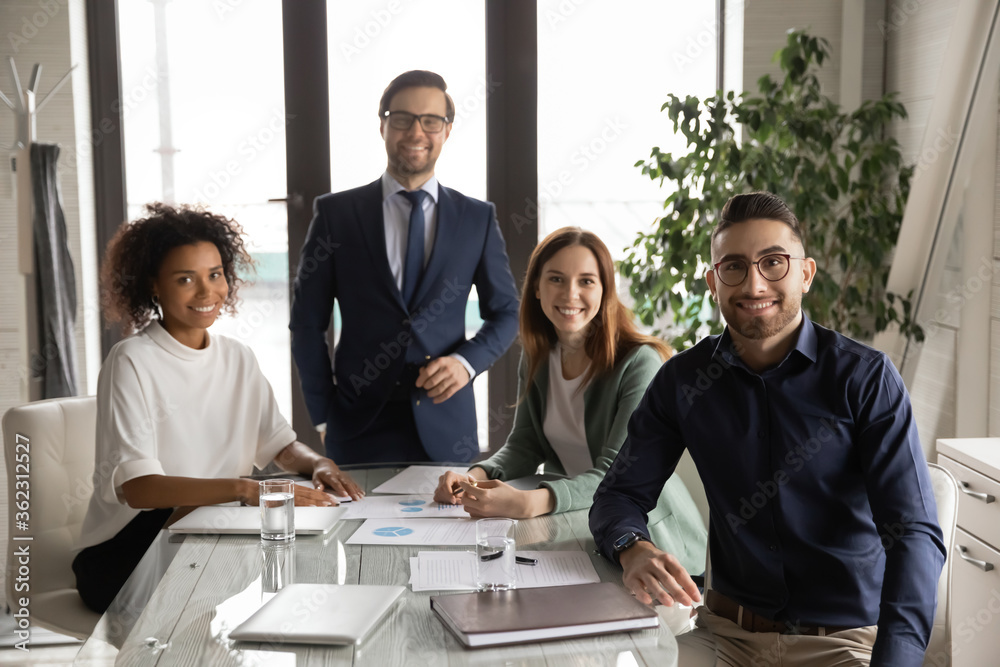 Portrait Of Smiling Multiracial Young Businesspeople Sit At Desk In