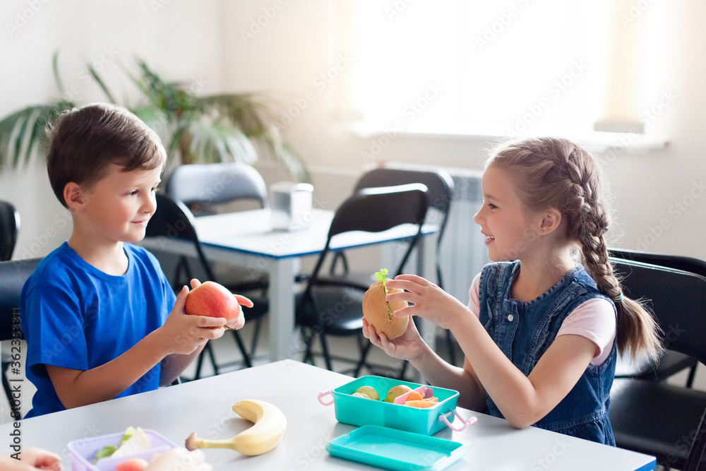 School kids eating healthy food together. Happy children sitting at ...