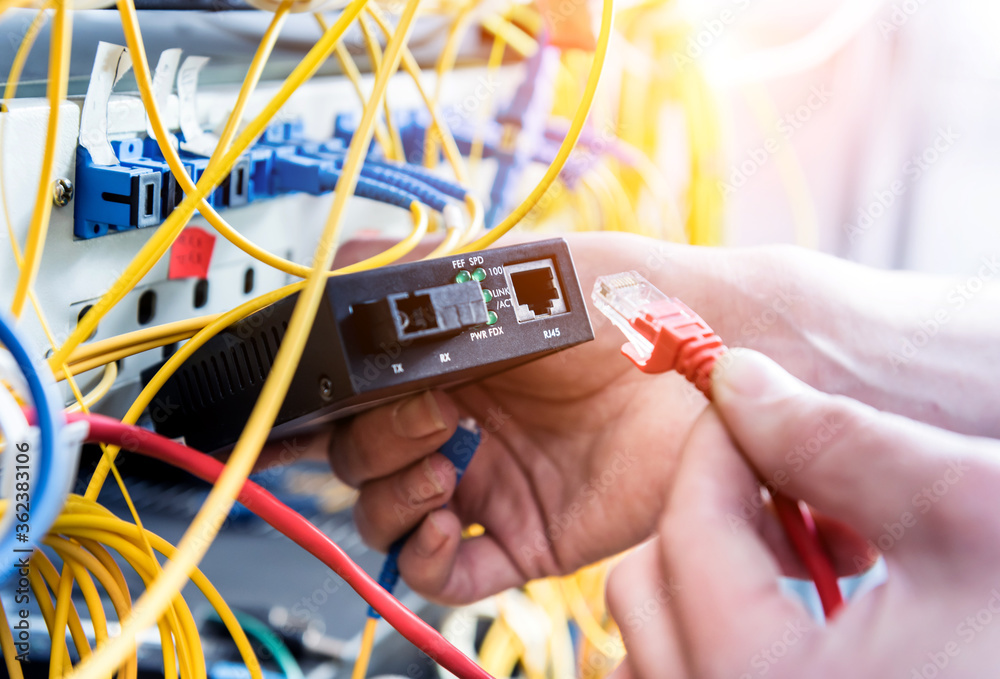 Network engineer working in server room. Connecting network cables to ...