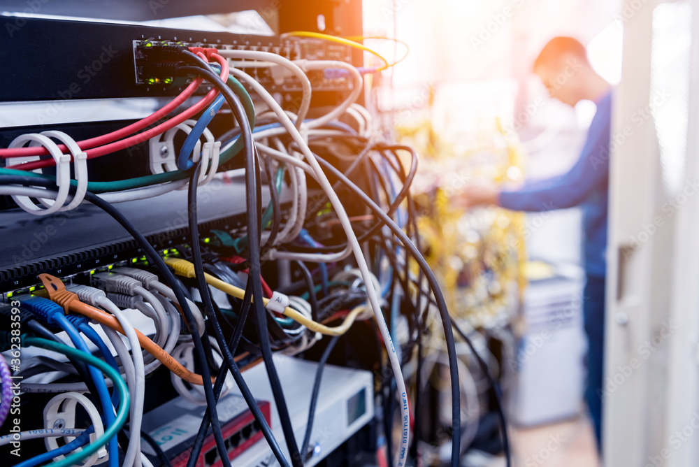 Network engineer working in server room. Connecting network cables to ...