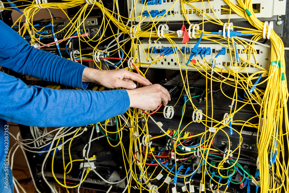 Network engineer working in server room. Connecting network cables to ...