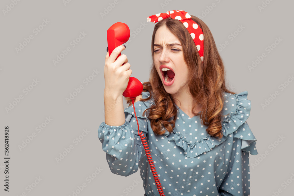 Irritated pinup girl shouting into phone handset, yelling scolding ...