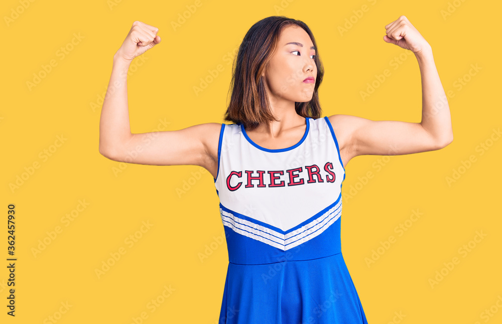 Young beautiful chinese girl wearing cheerleader uniform showing arms ...