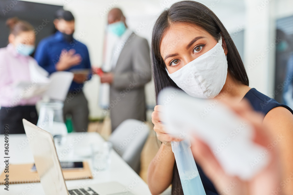 Businesswoman using everyday mask while disinfecting computer Stock ...