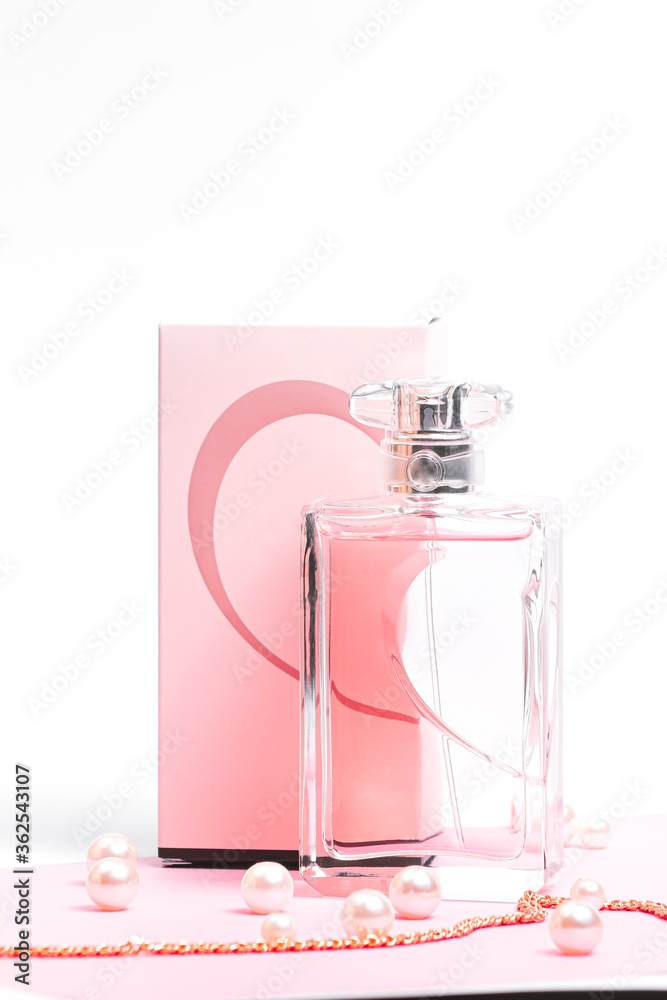 pink perfume bottle with pearls and a gold chain on the back of a box ...