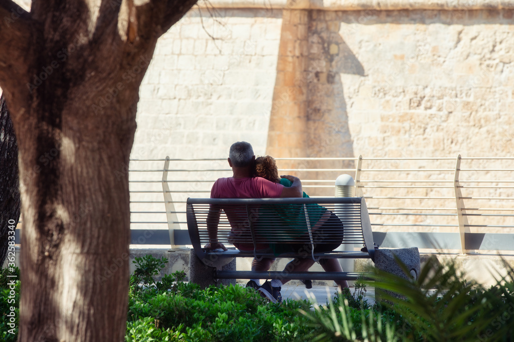 Back view of happy lovely caucasian romantic couple sitting in bench ...