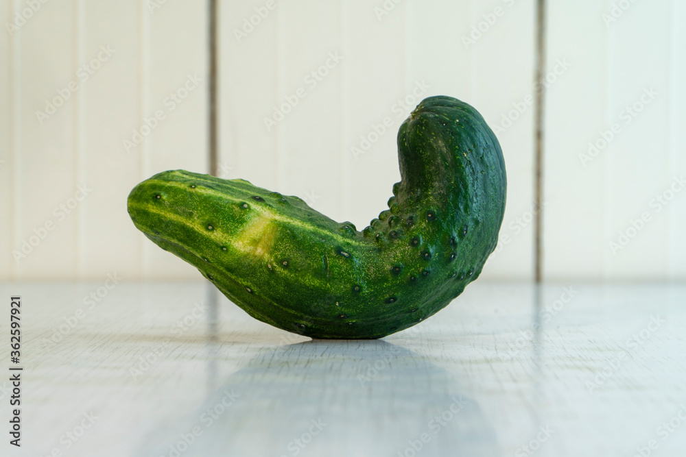 Foto de Deformed homegrown cucumber lying on the table in light kitchen ...