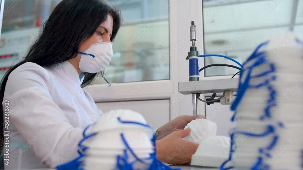 The girl works in a factory for the production of medical masks with ...