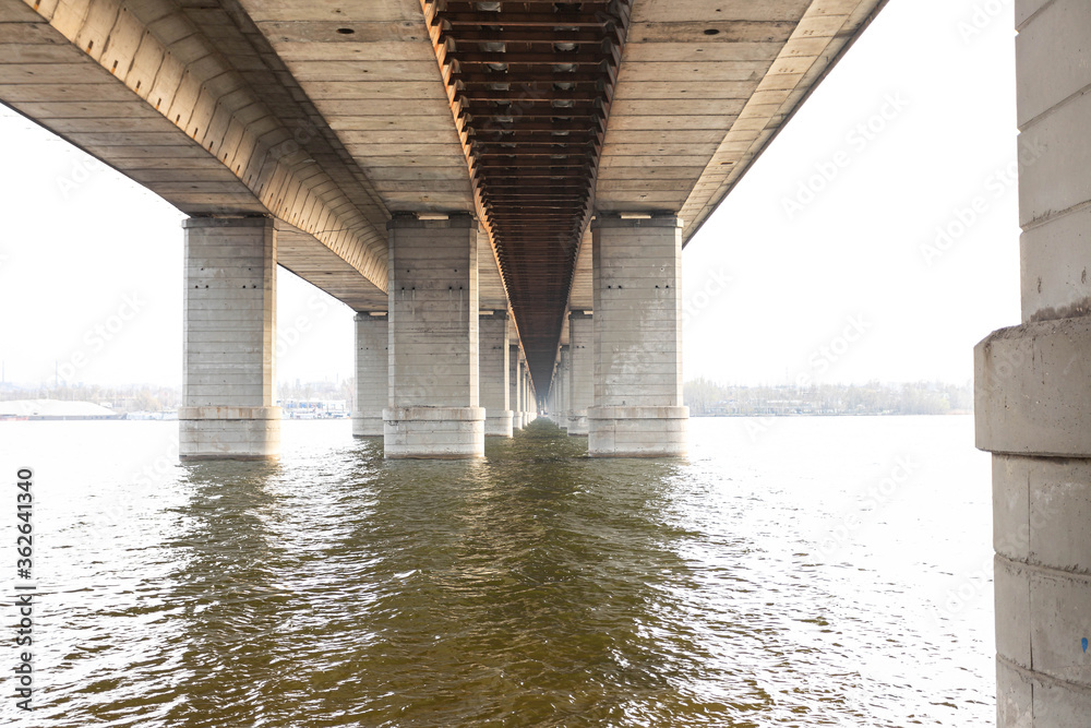 Grey concrete pillars of the bridge over the river. Bridge piers, sky ...
