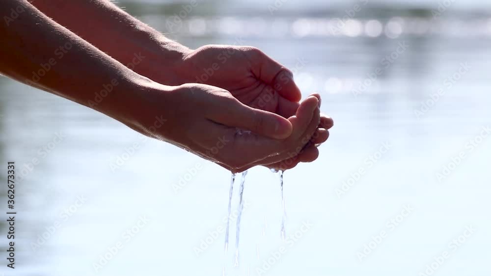 Slow-motion close-up loop shot of hands holding river water. Bright sun ...