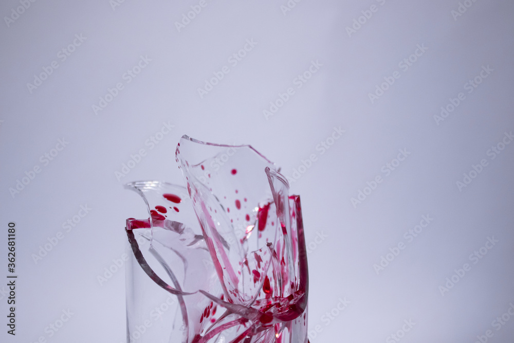 drops of red liquid - blood - on the fragments of a broken glass in a ...