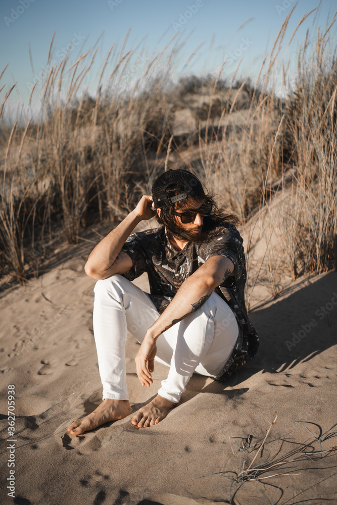 Modelo de estilo surfero con pelo largo, gafas de sol y gorra, en unas ...