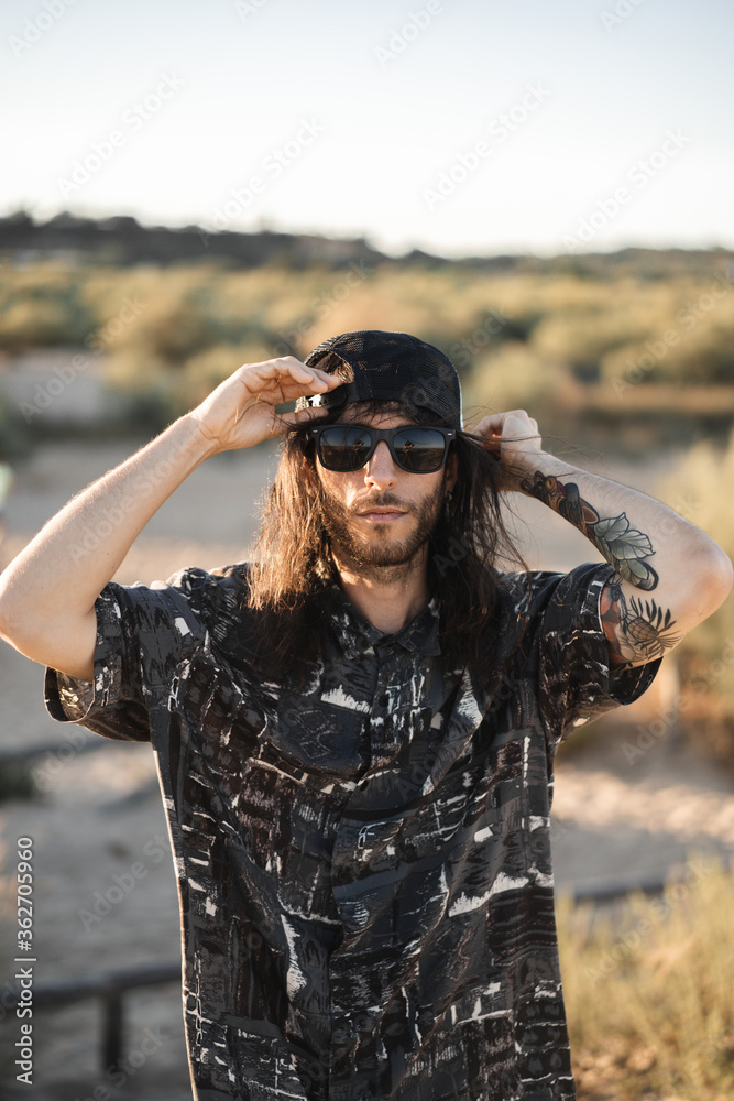 Modelo de estilo surfero con pelo largo, gafas de sol y gorra, en unas ...
