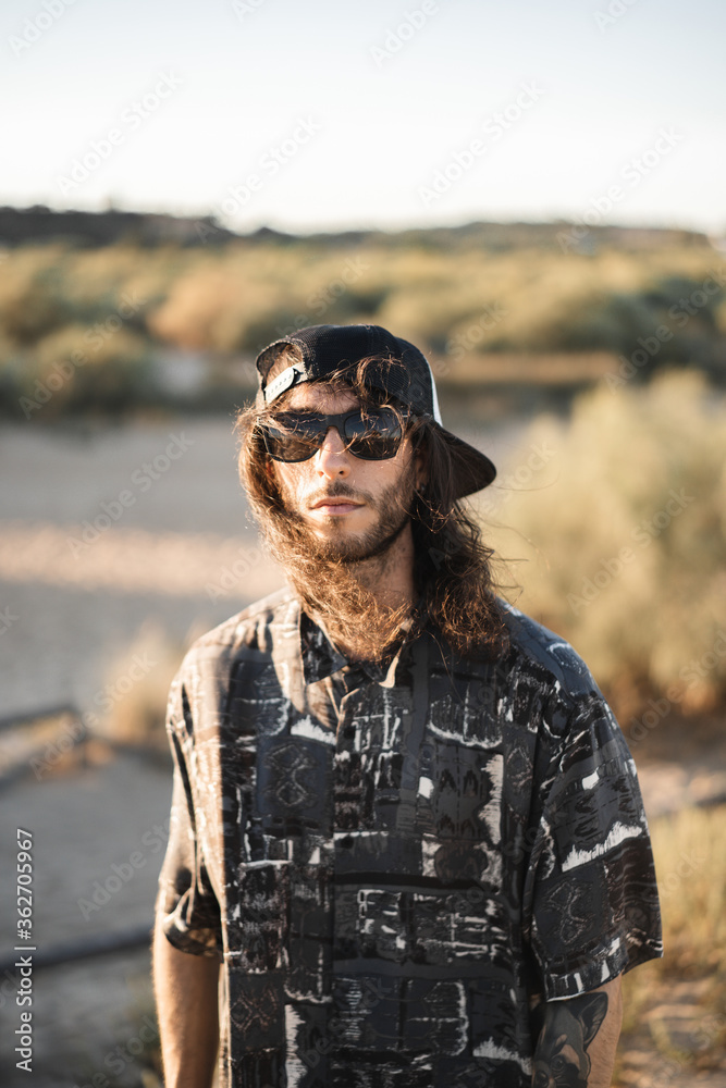 Modelo de estilo surfero con pelo largo, gafas de sol y gorra, en unas ...