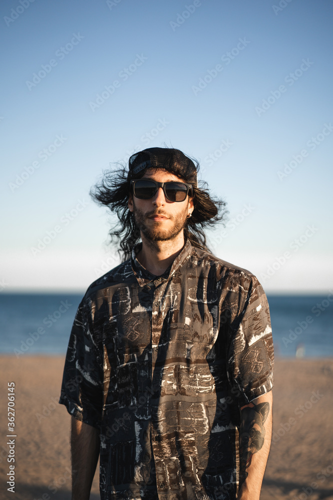 Modelo de estilo surfero con pelo largo, gafas de sol y gorra, en unas ...