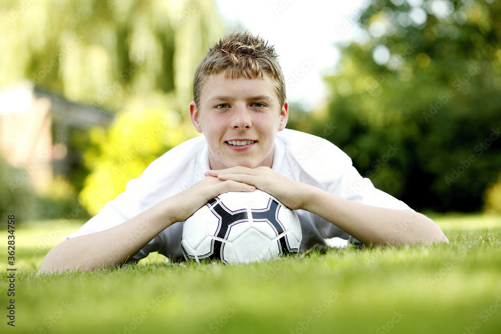 Foto de Teenage boy lying forward on the field with his chin resting on ...