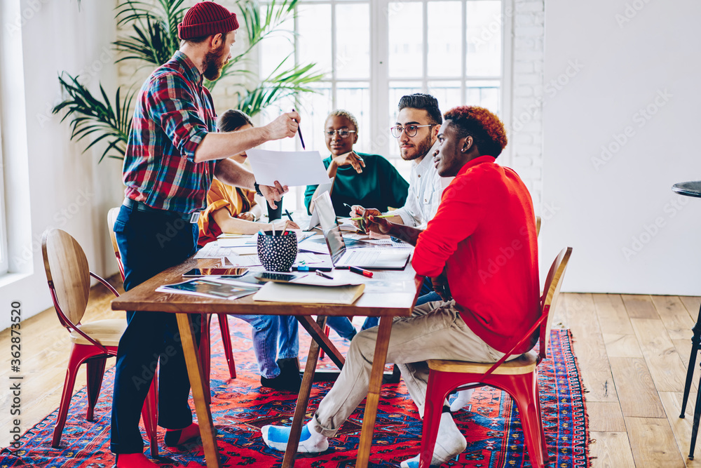 Skilled male employee presenting his strategy to multiracial crew of ...
