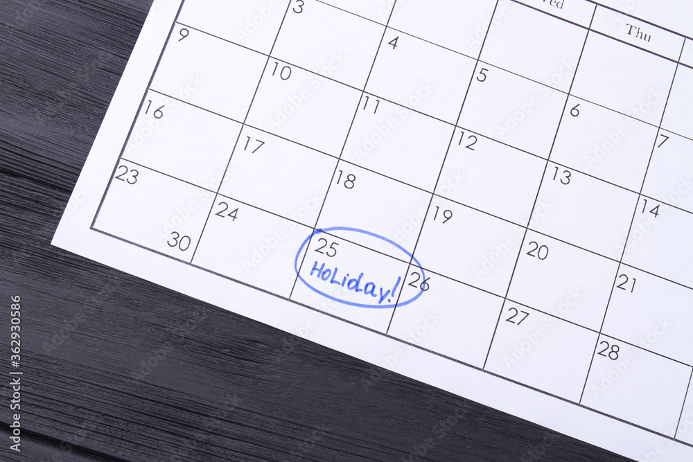 Paper calendar with a marked holiday. Day circled by a blue marker ...