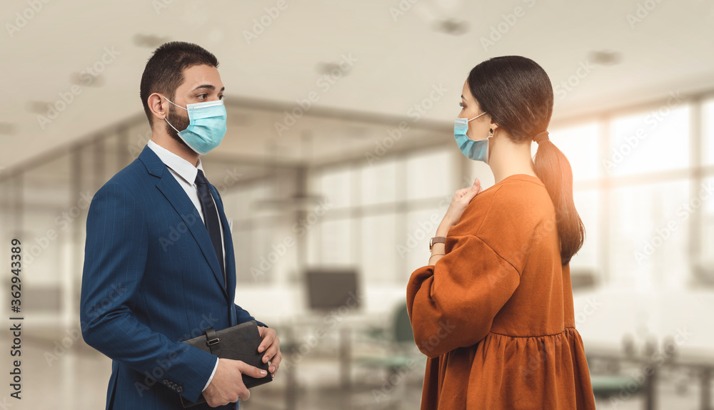Two employee standing in social distance wearing face mask looking at ...