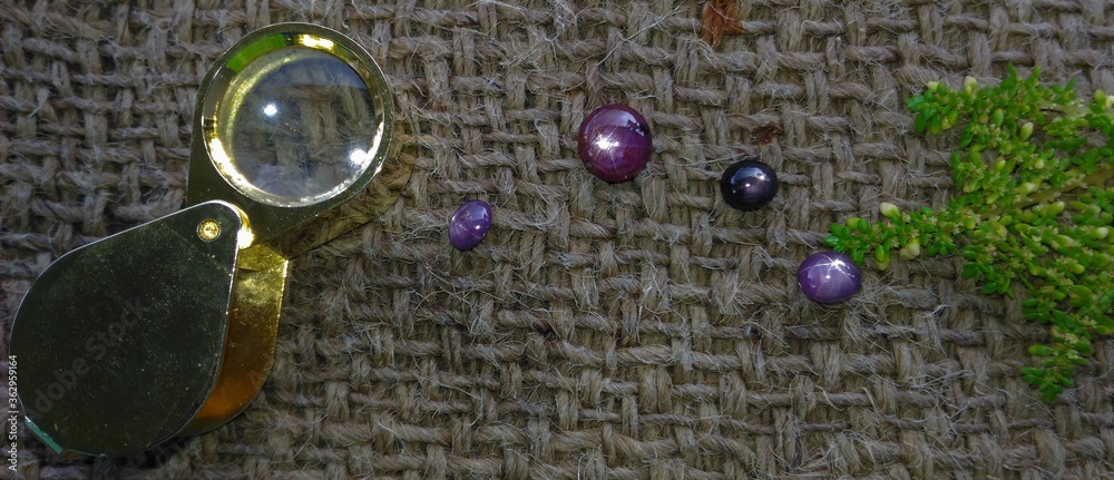 On a jute cloth, a gem loupe and different types of precious gemstones ...