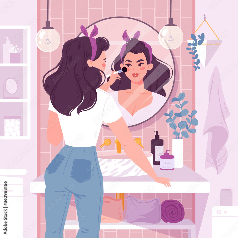 Young woman standing in front of a mirror applies makeup in bathroom ...