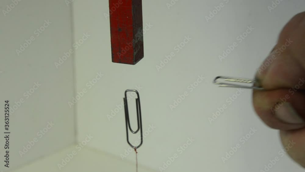 Stockvideon A paperclip hovers under a magnet, kept down by a string ...