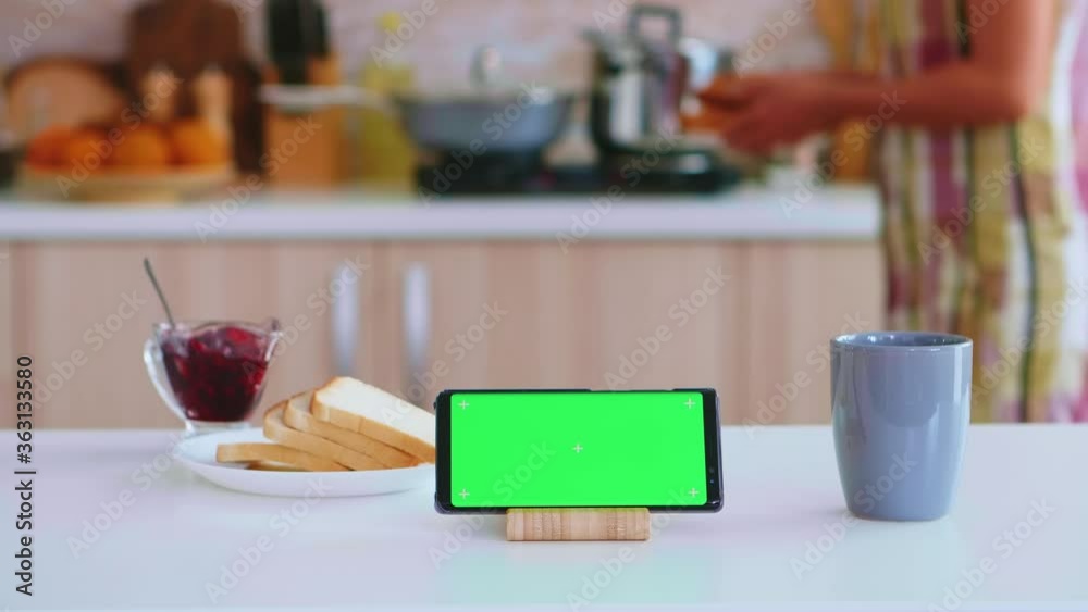 Copy space available on smartphone in kitchen while woman is holding ...