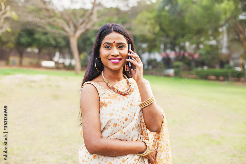Beautiful indian woman in saree talking on mobile phone, standing in ...