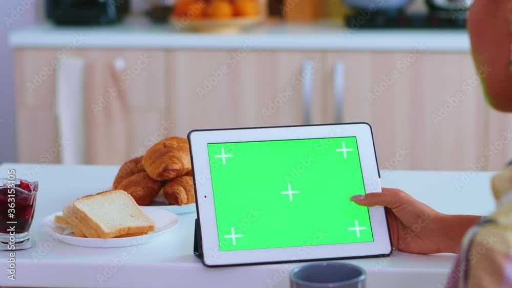 Woman searching recipe on table computer with green mockup in kitchen ...