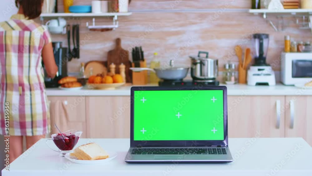 Laptop with green screen with kitchen and woman holding plate with ...